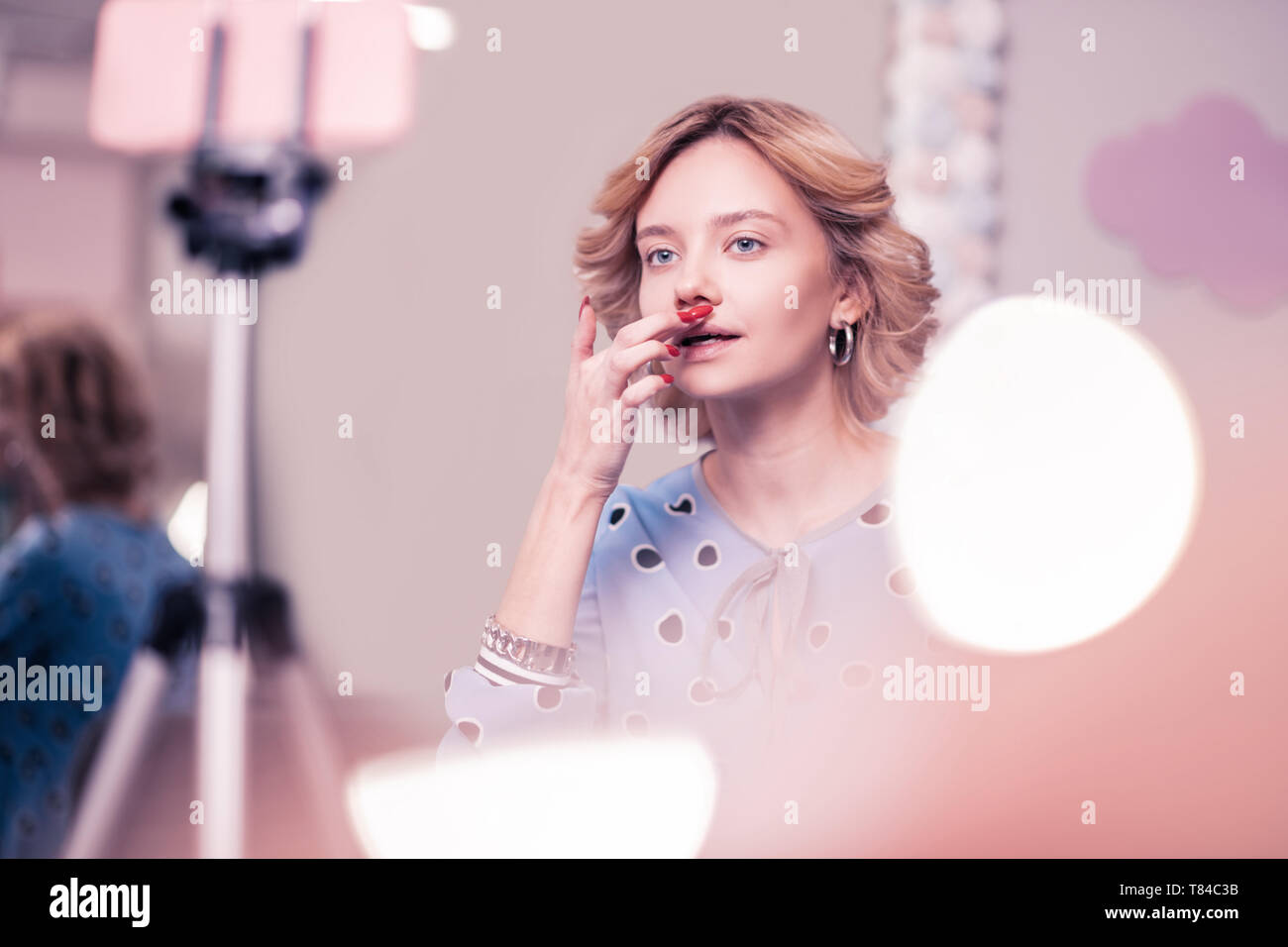 Blogger with red nails putting some concealer above upper lip Stock ...