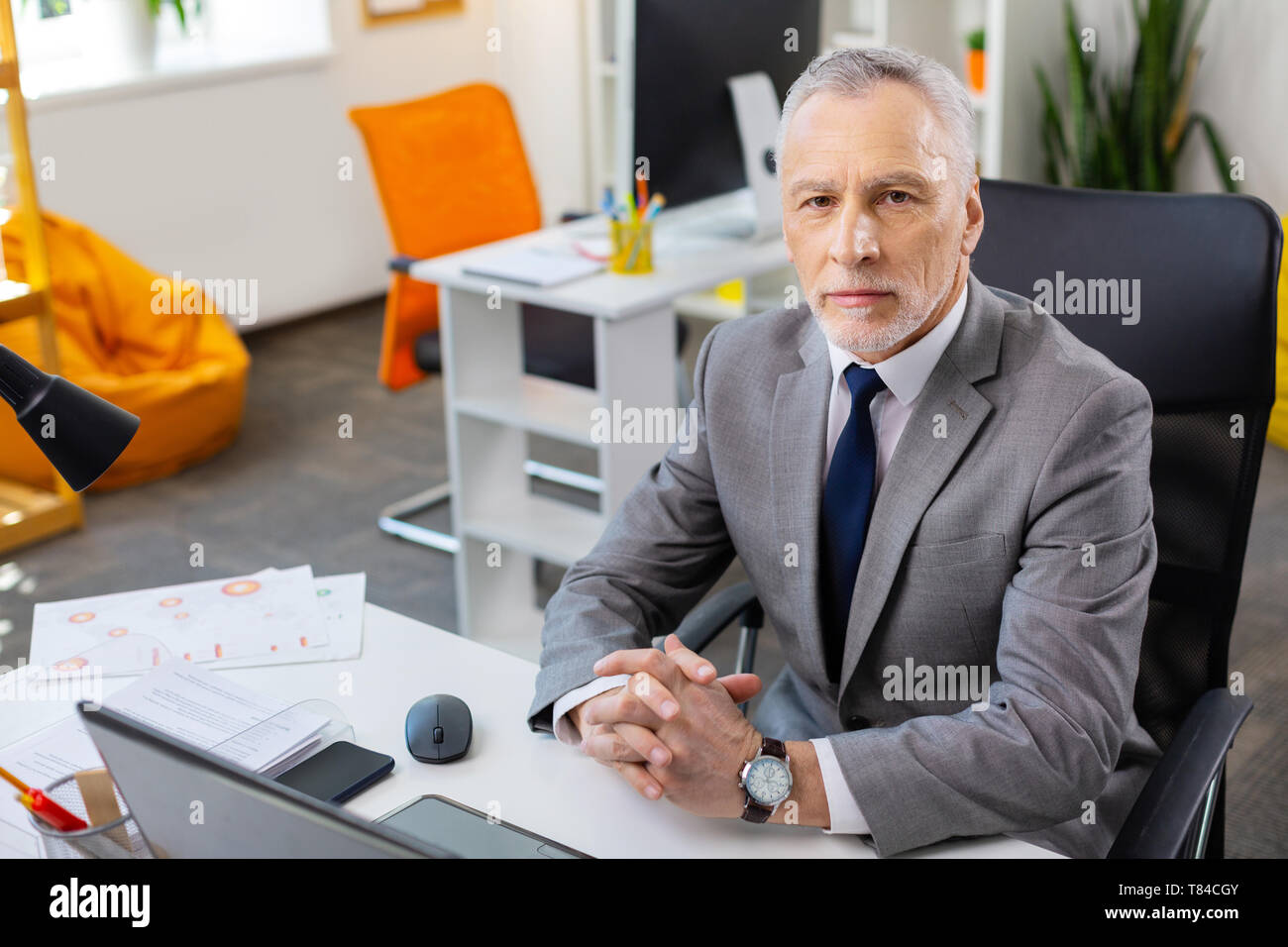 Grey-haired strict man in grey costume being concentrated at work Stock ...
