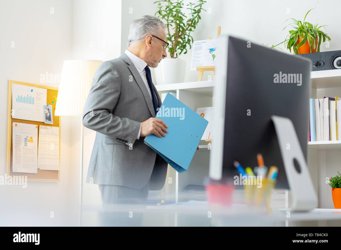 Active senior office worker taking blue fold from the shelves Stock ...