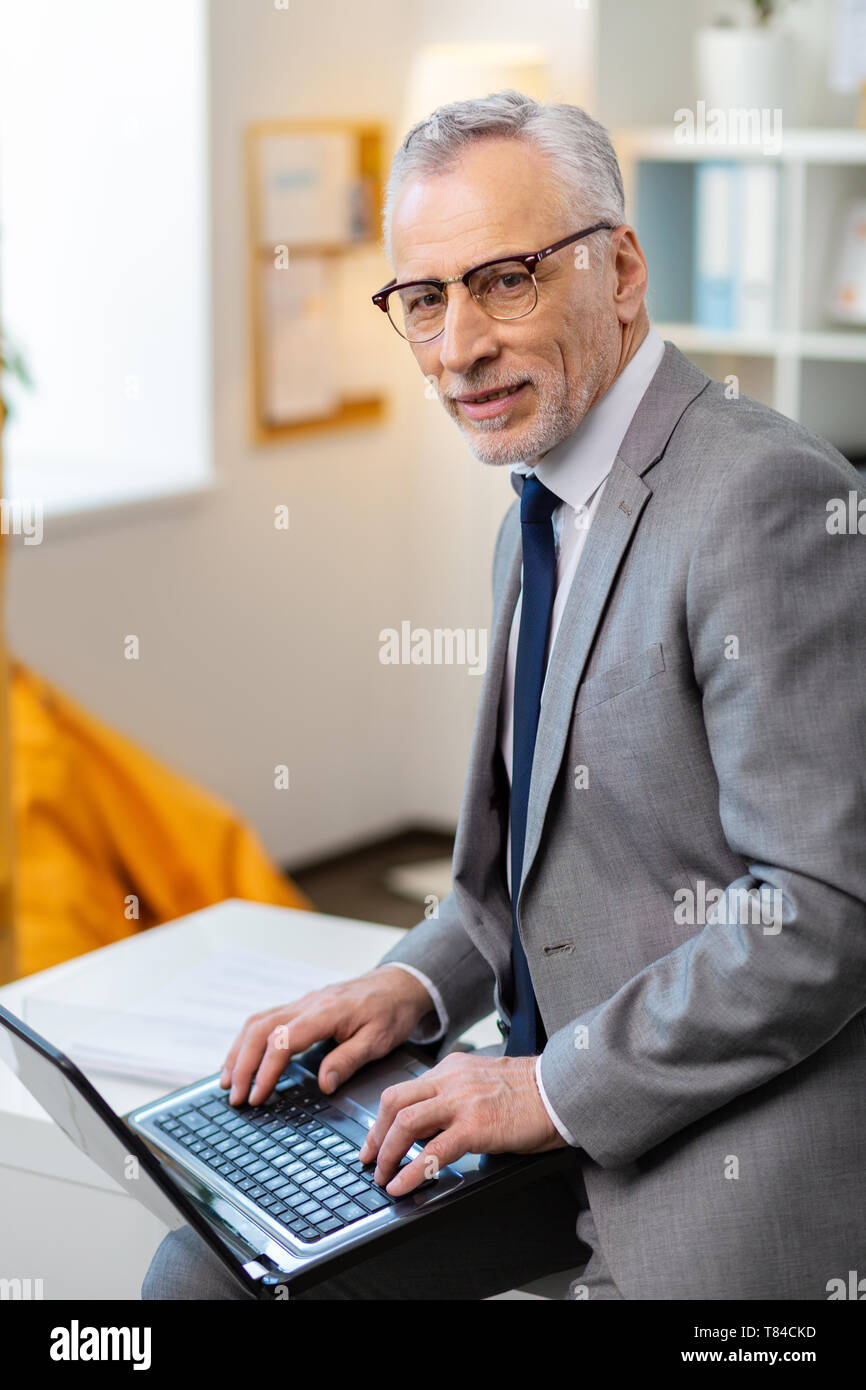 Pleasant calm office worker finishing working day and closing affairs ...