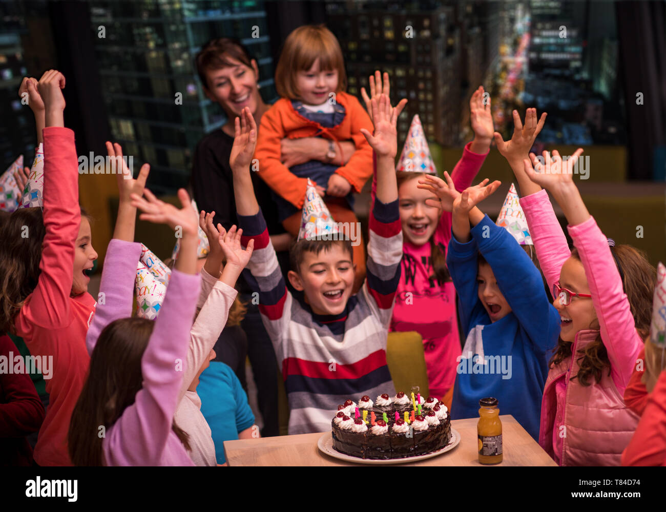 young happy boy and group of his friends having birthday party with a ...