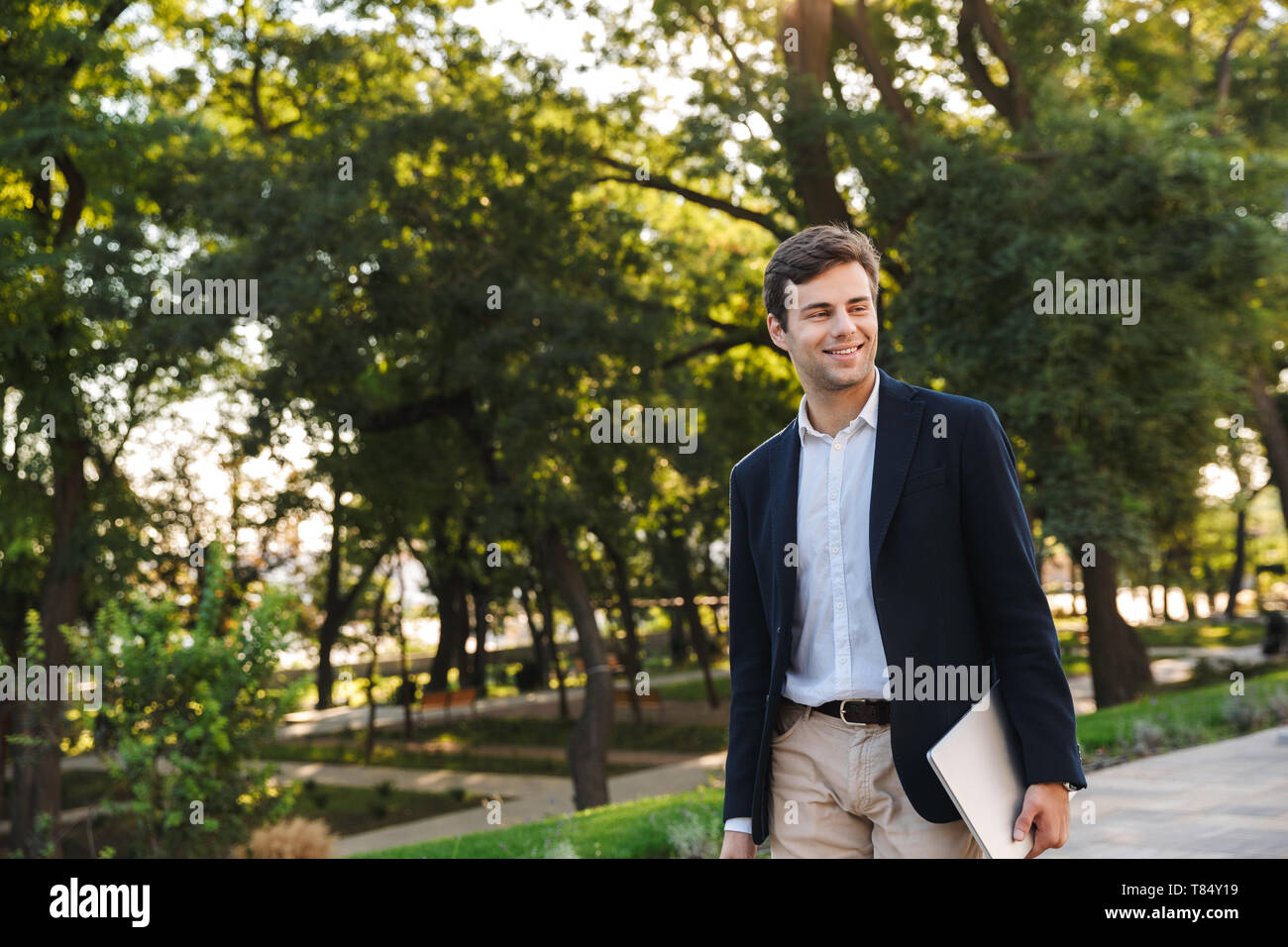 Confident business man walking outdoors, carrying a laptop Stock Photo ...