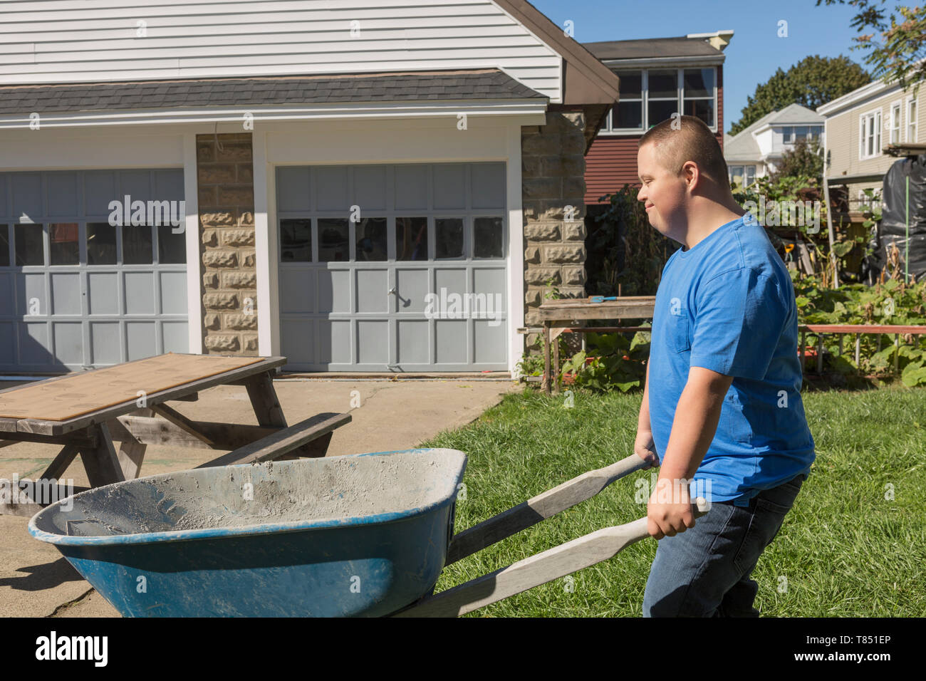 Teen with Down Syndrome carrying wheelbarrow Stock Photo - Alamy