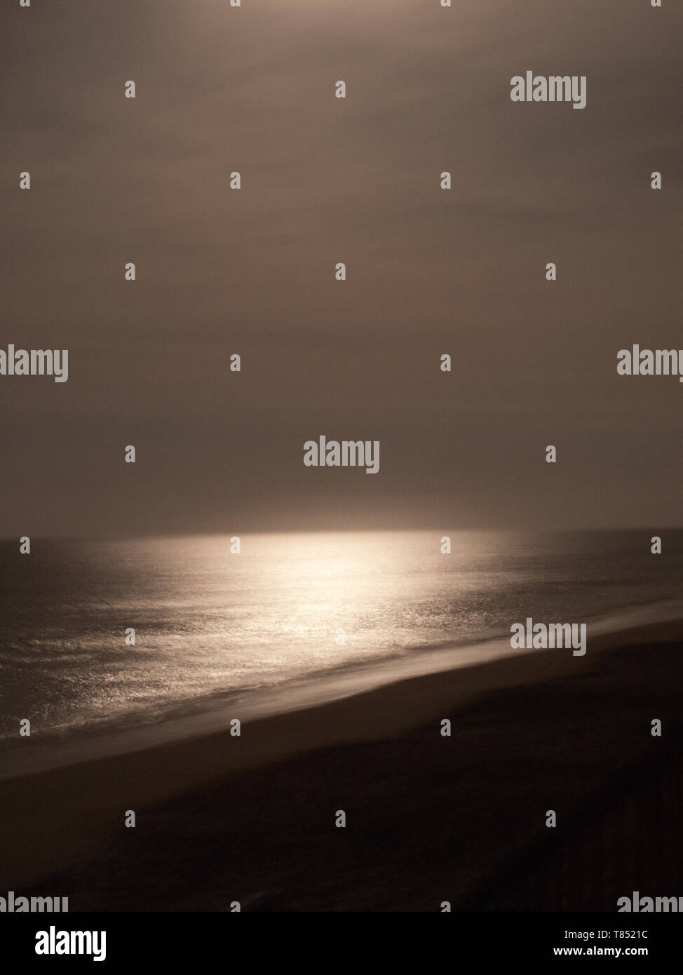 View over the water from shore at night, reflection of the moon on the ...