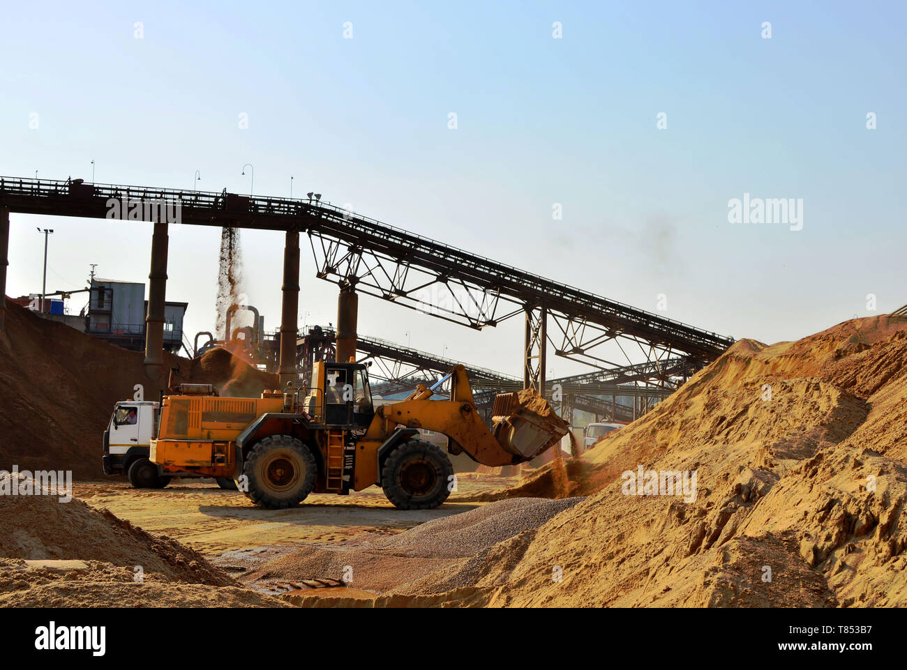 Wheel front-end loader unloading sand into heavy dump truck. Crushing ...