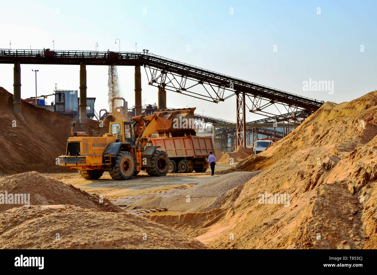 Wheel front-end loader unloading sand into heavy dump truck. Crushing ...