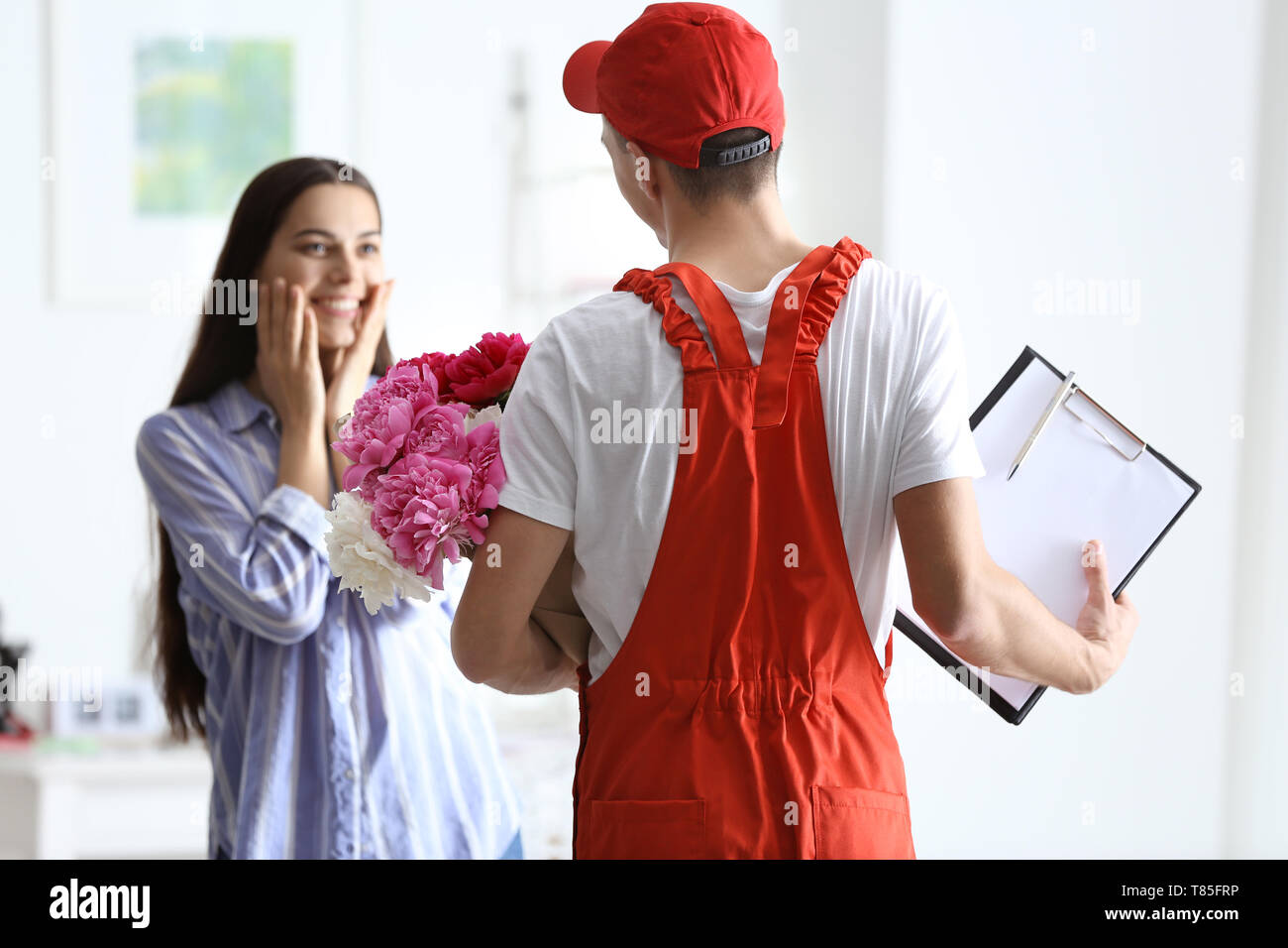 Young woman receiving beautiful flowers from delivery man Stock Photo ...