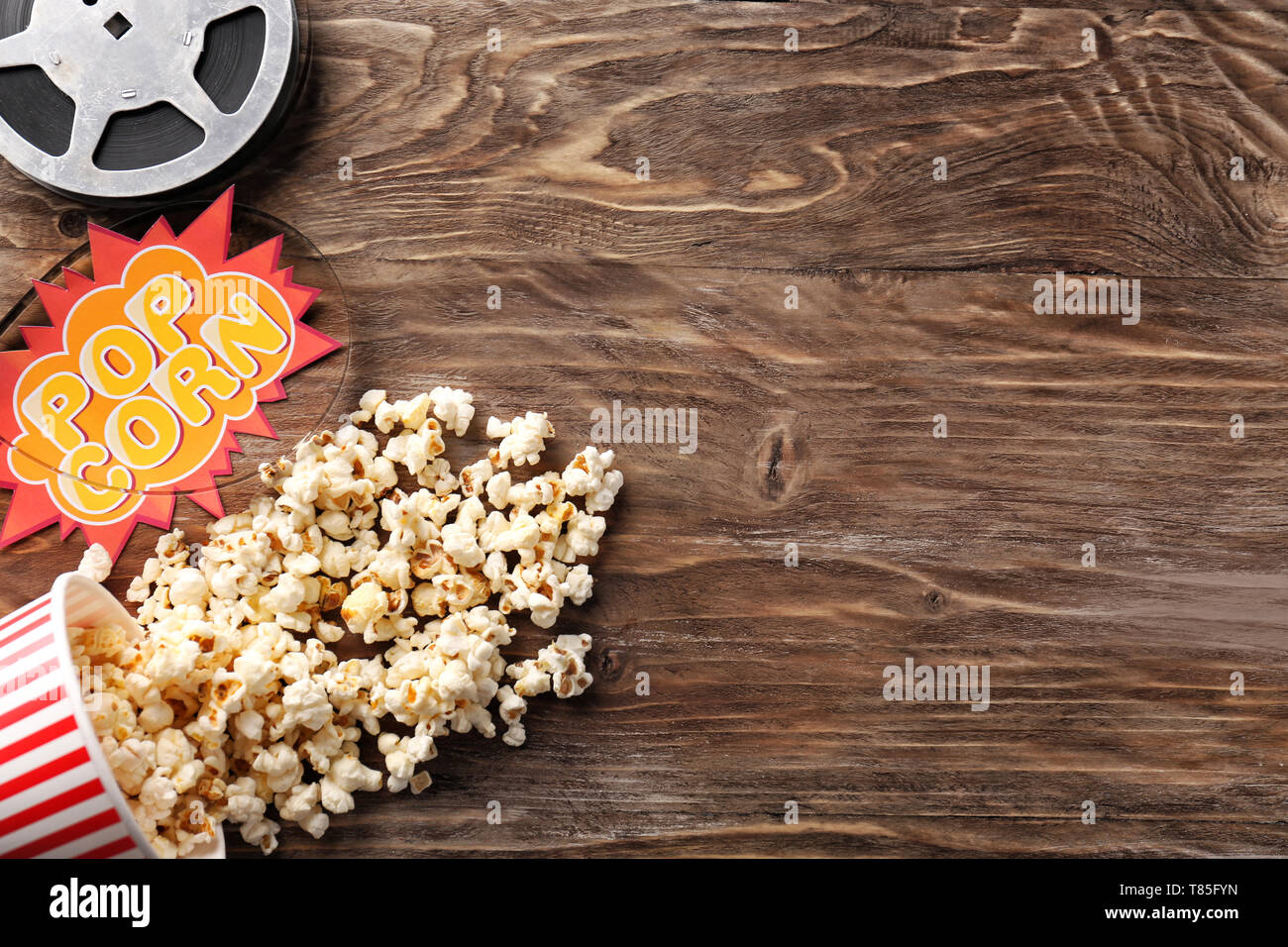 Composition with tasty popcorn and film reel on wooden background Stock ...