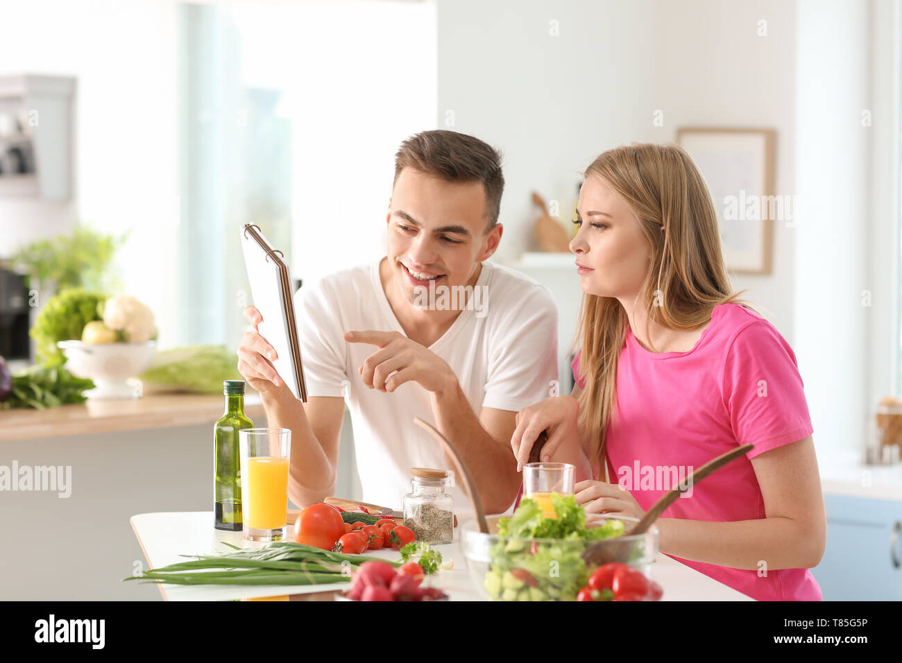 Friends with recipe book cooking together in kitchen Stock Photo - Alamy