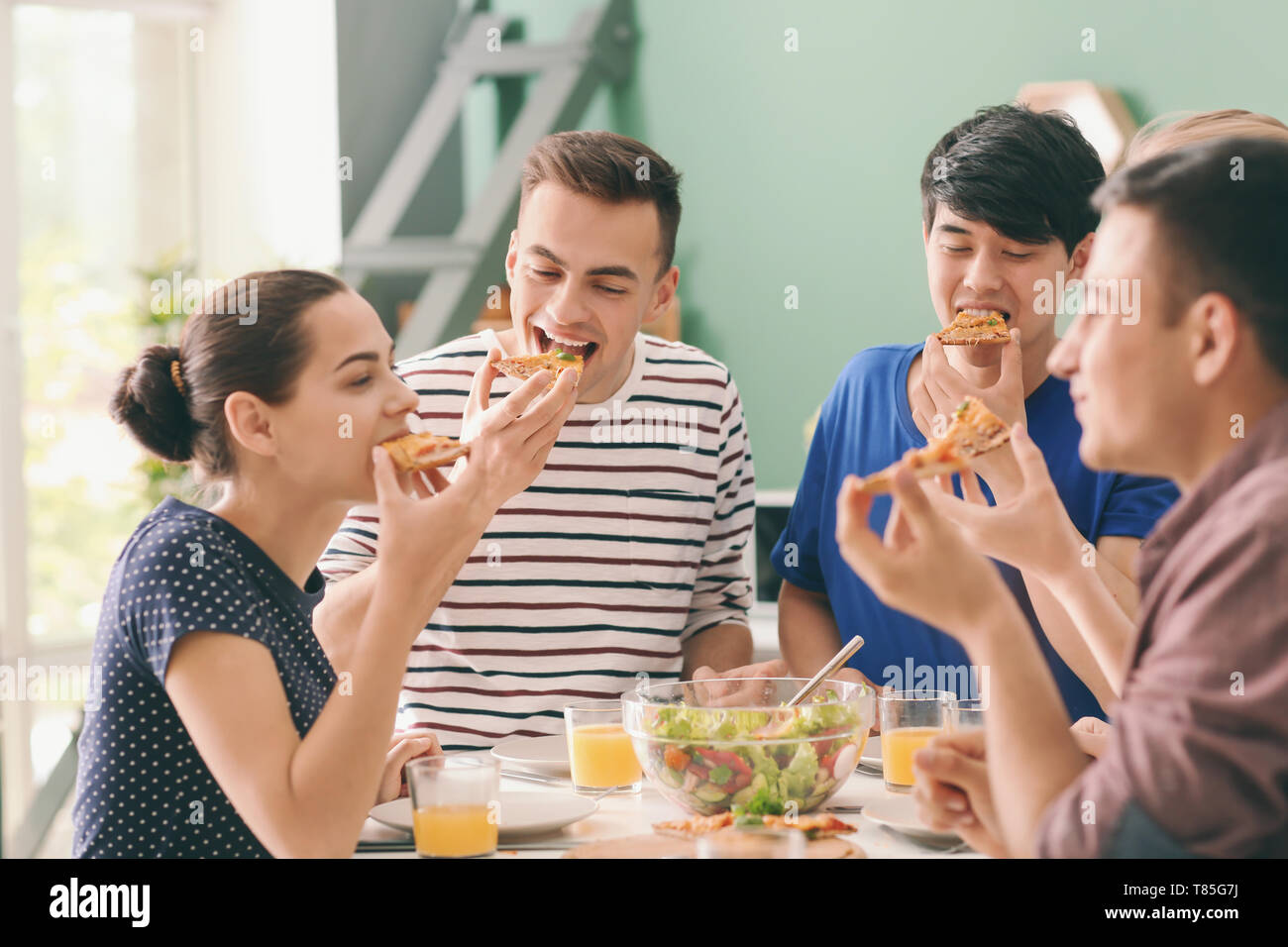 Friends eating at table in kitchen Stock Photo - Alamy
