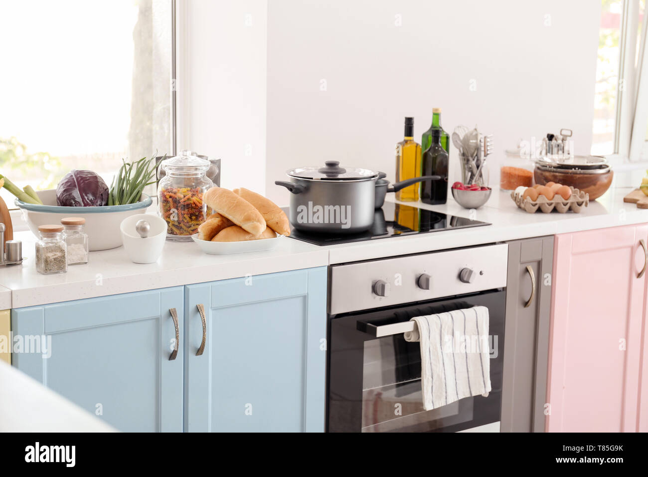 Electric stove with stewpan and products on table in modern kitchen ...