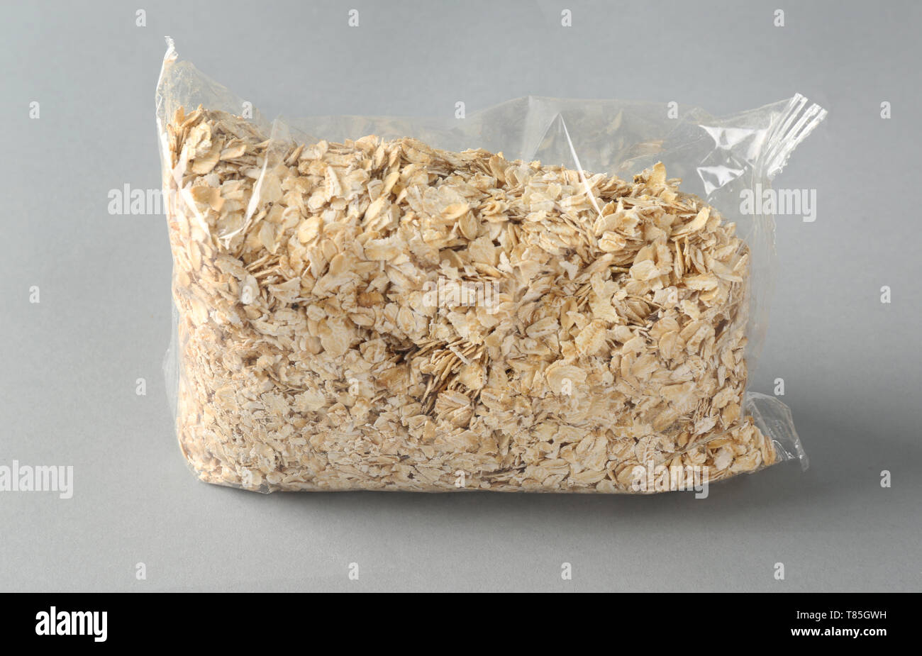 Package with raw oatmeal on light background Stock Photo - Alamy
