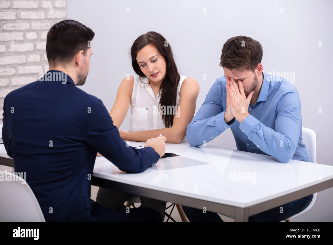 Rear View Of Financial Advisor Sitting With Depressed Young Couple ...