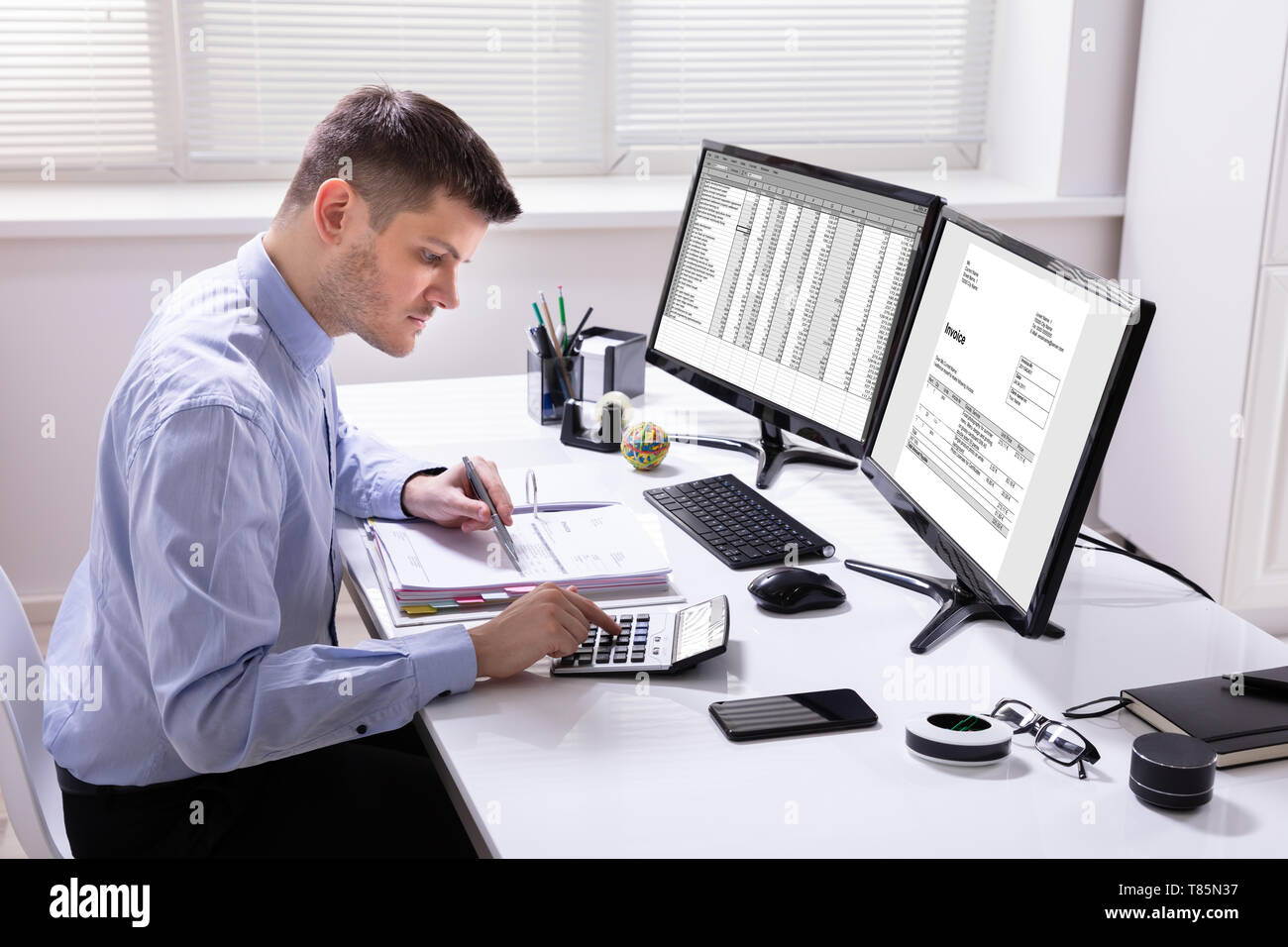 Young Businessman Calculating Invoice On Computer Screen Using ...