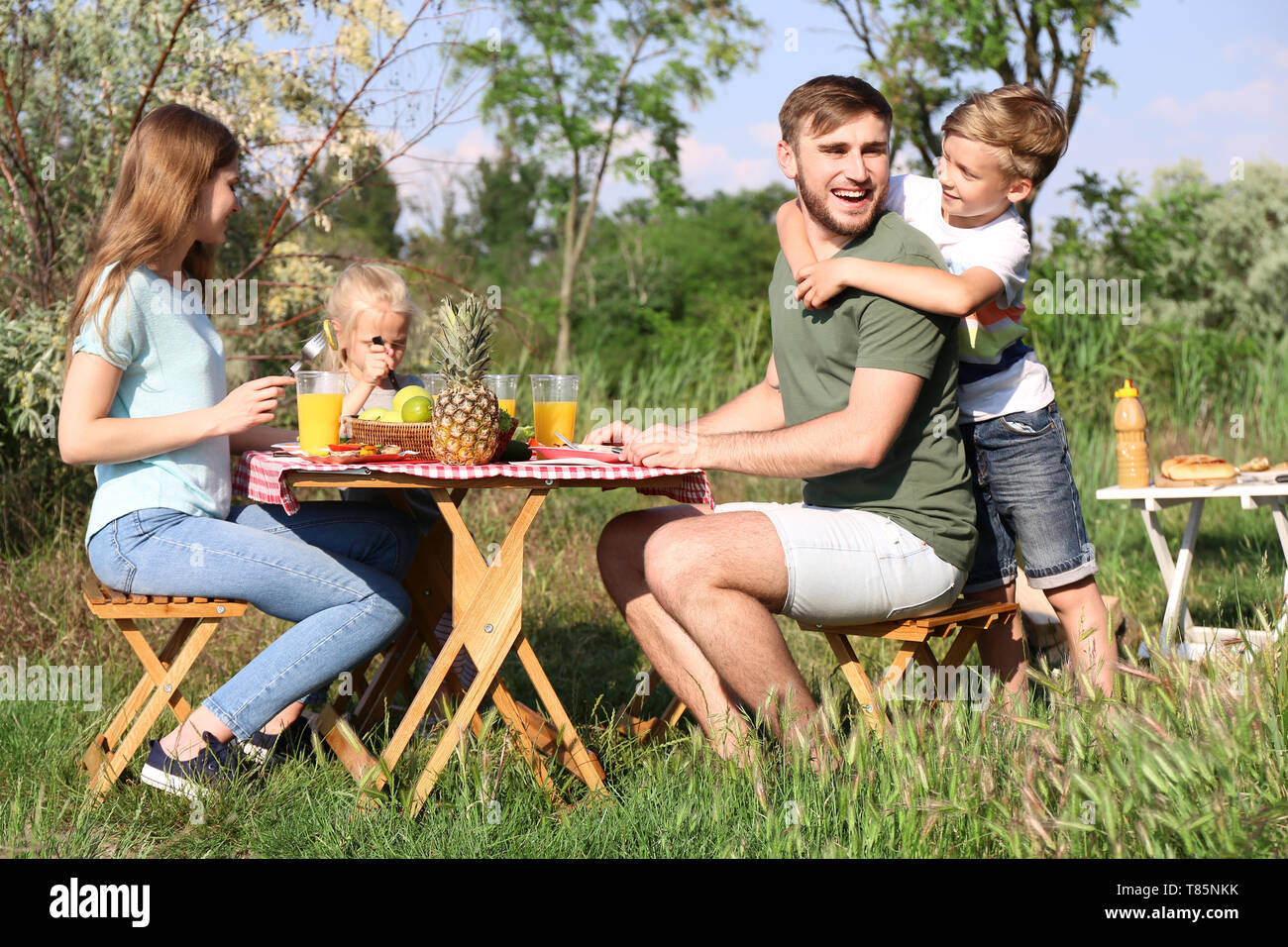 Happy family having lunch at table on summer picnic Stock Photo - Alamy