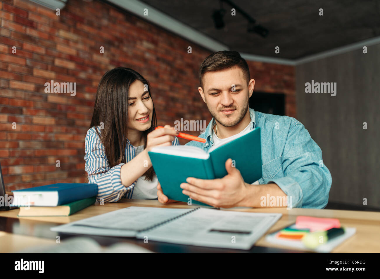 University students reading textbook together Stock Photo - Alamy