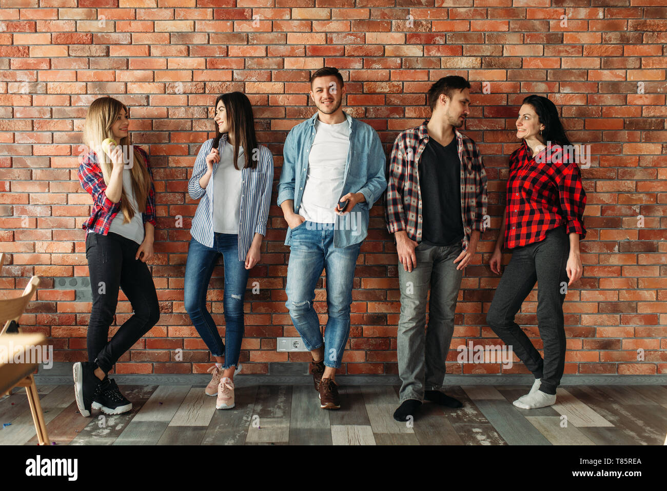 Group of students standing at the brick wall Stock Photo - Alamy