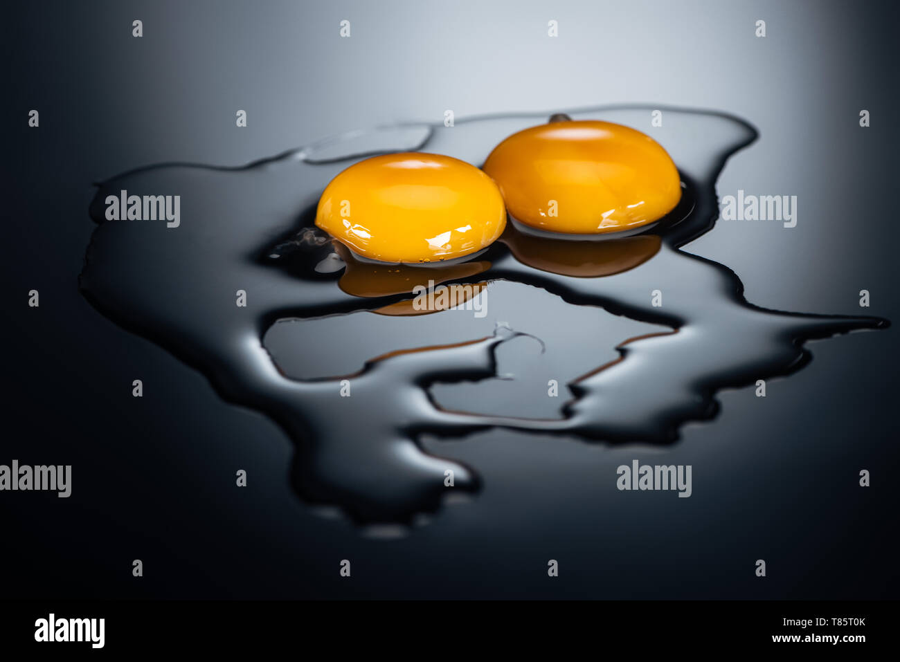 raw chicken yolks and proteins on black background Stock Photo - Alamy