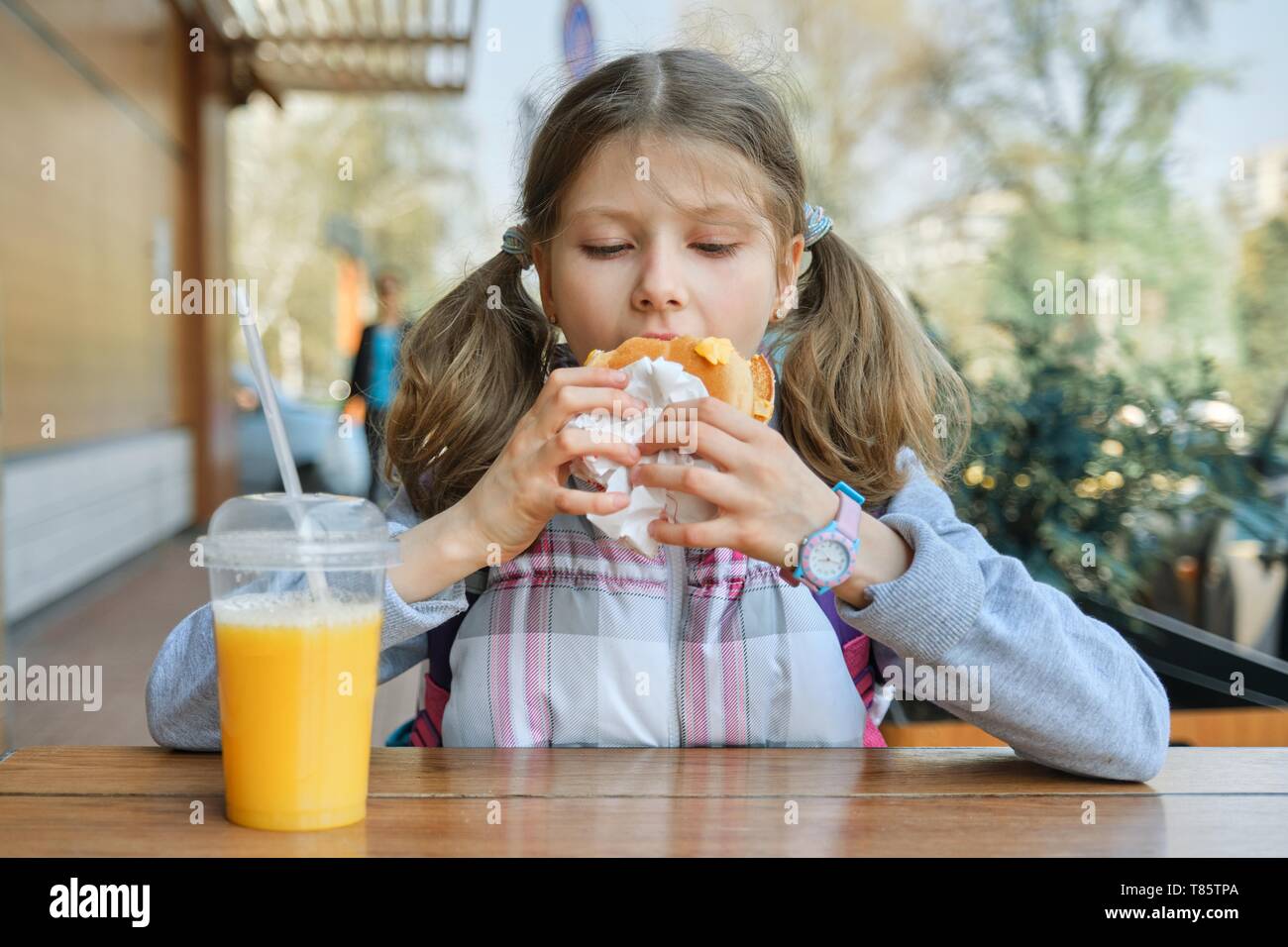 Portrait of girl student with backpack, eating burger with orange juice ...