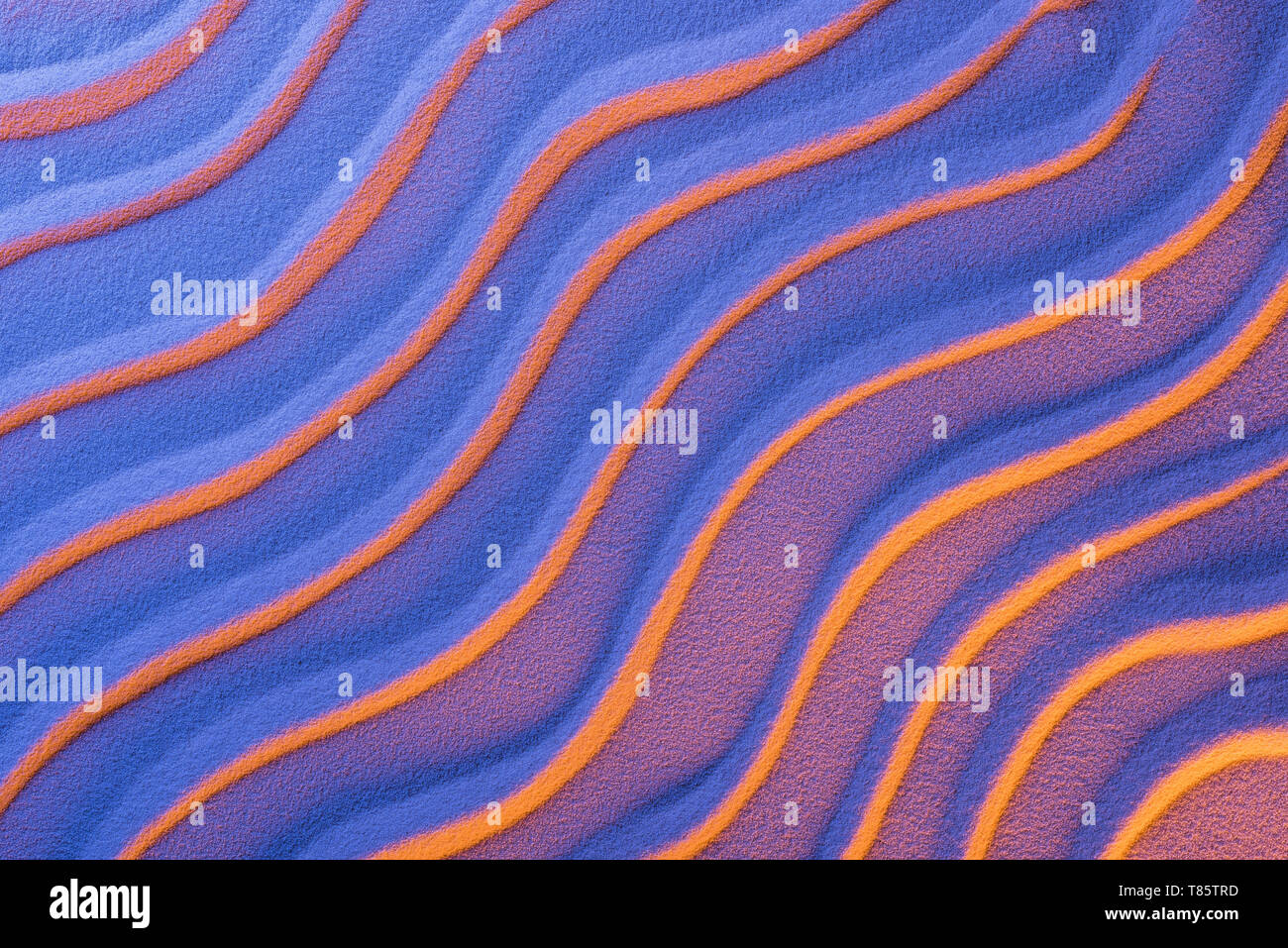 top view of textured sand with smooth waves and neon purple color ...