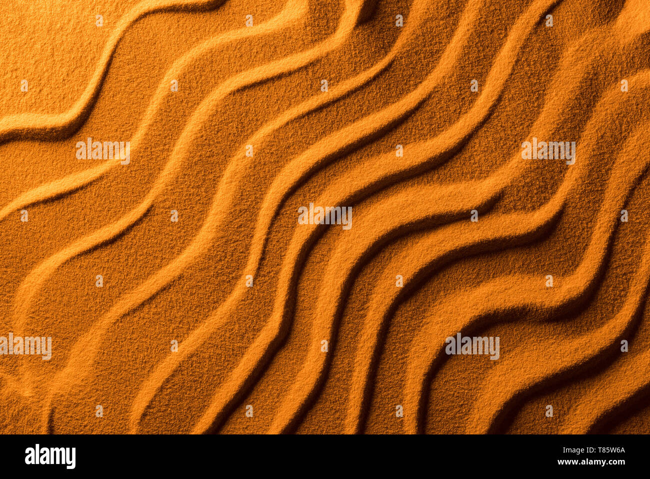 top view of sandy background with smooth waves and orange color filter ...