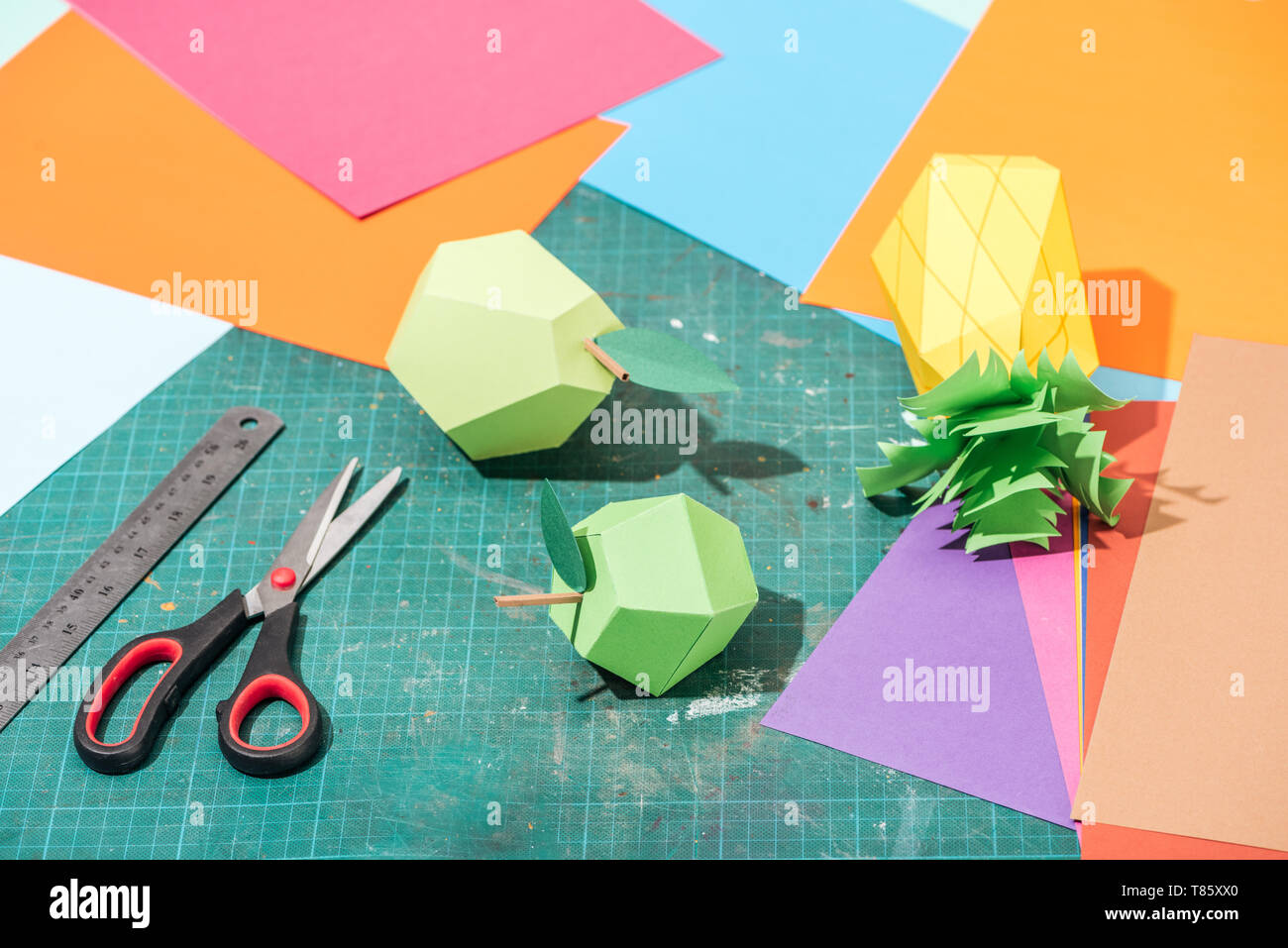origami fruits and colorful cardboard with scissors and ruler on messy ...