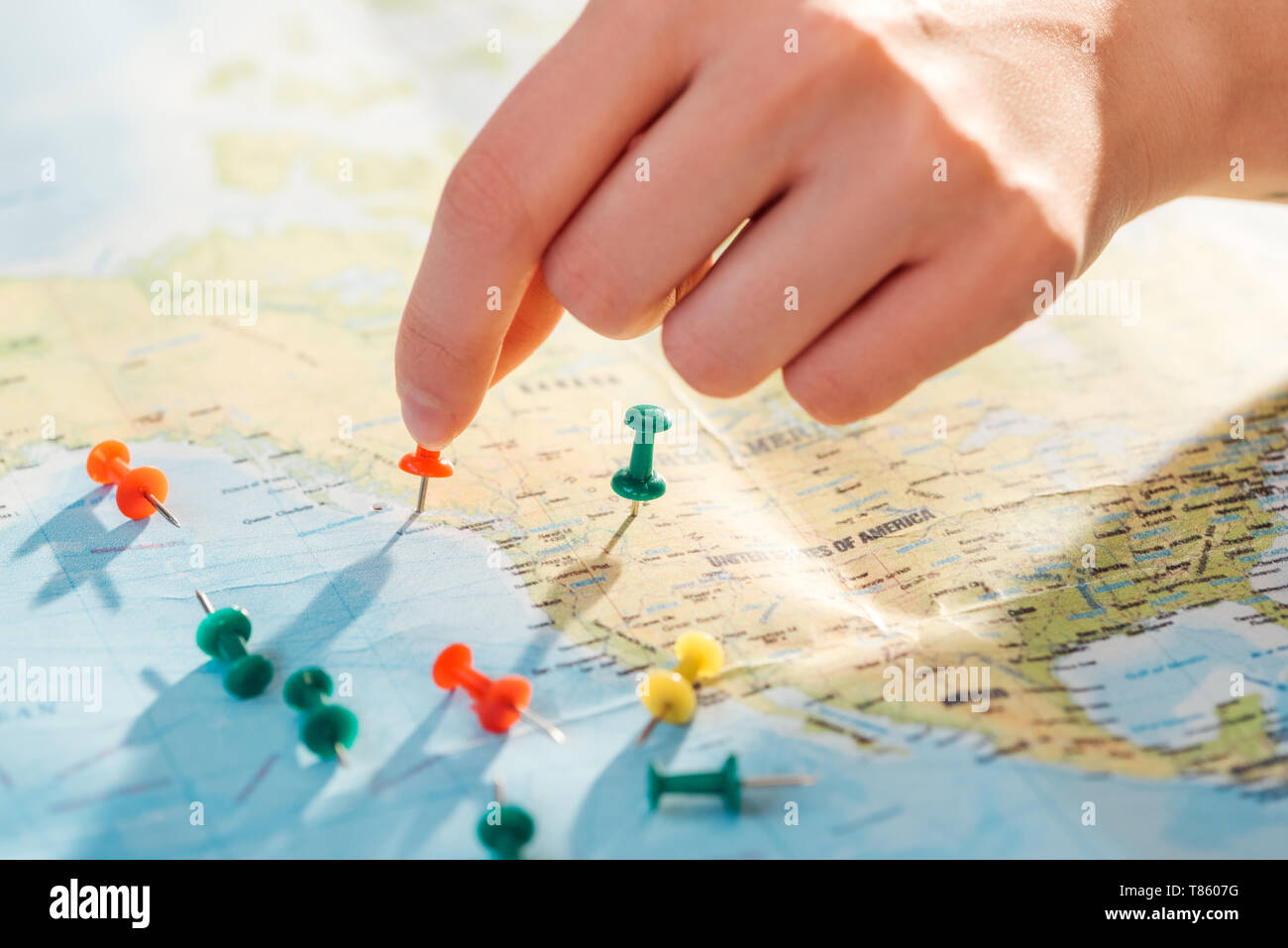 Partial view of woman and colorful push pins on world map Stock Photo - Alamy