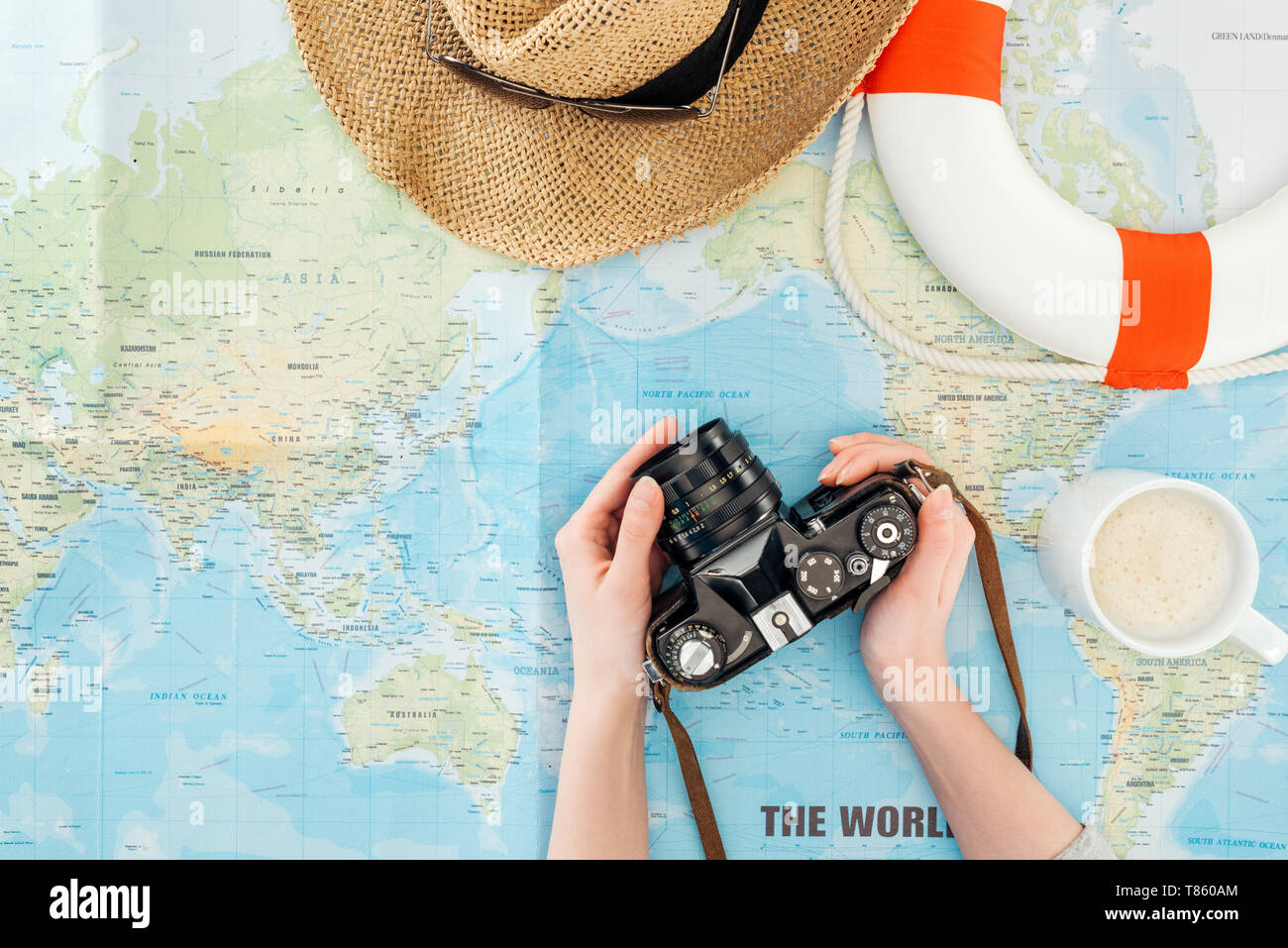 Cropped view of woman with straw hat and lifebuoy holding film camera ...
