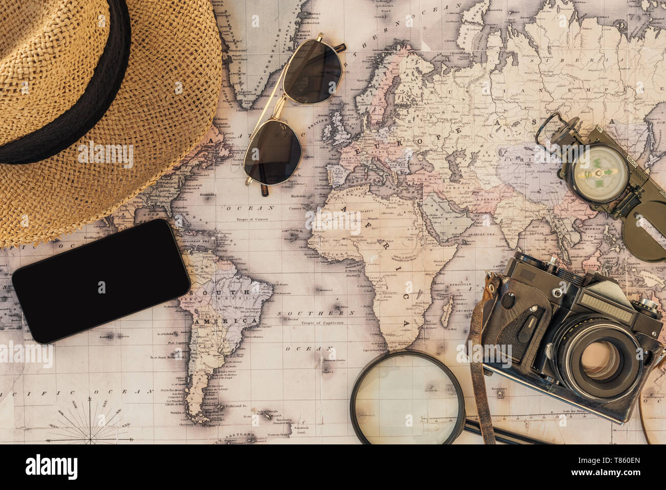 Top view of straw hat, sunglasses, film camera, magnifier, compass and ...