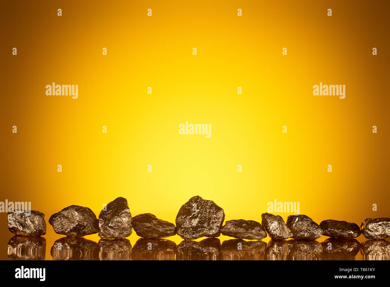 gold shiny stones with reflection on yellow illuminated background ...
