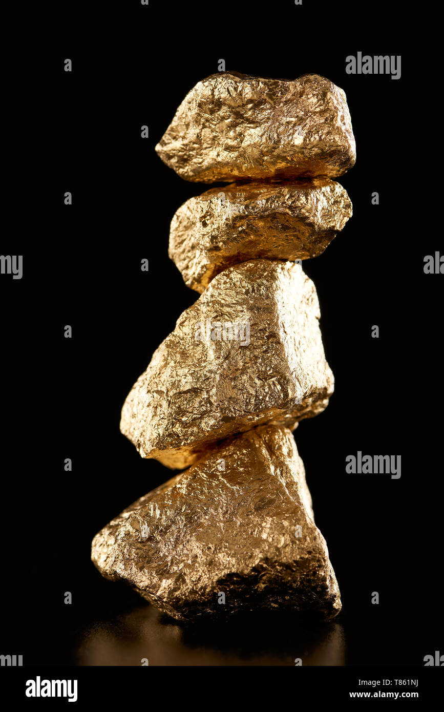 four golden textured shiny stones isolated on black Stock Photo - Alamy