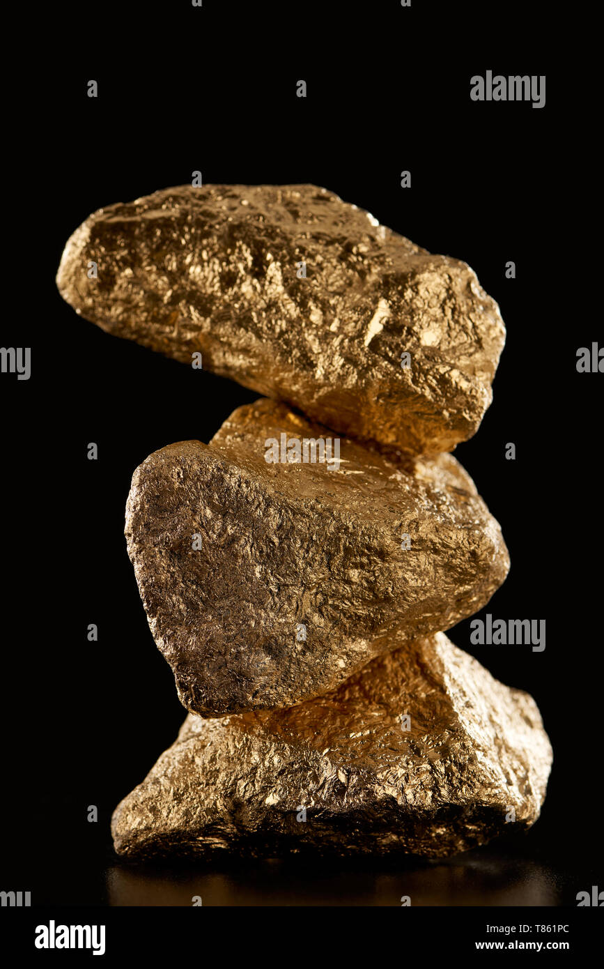 three gold textured shiny stones isolated on black Stock Photo - Alamy