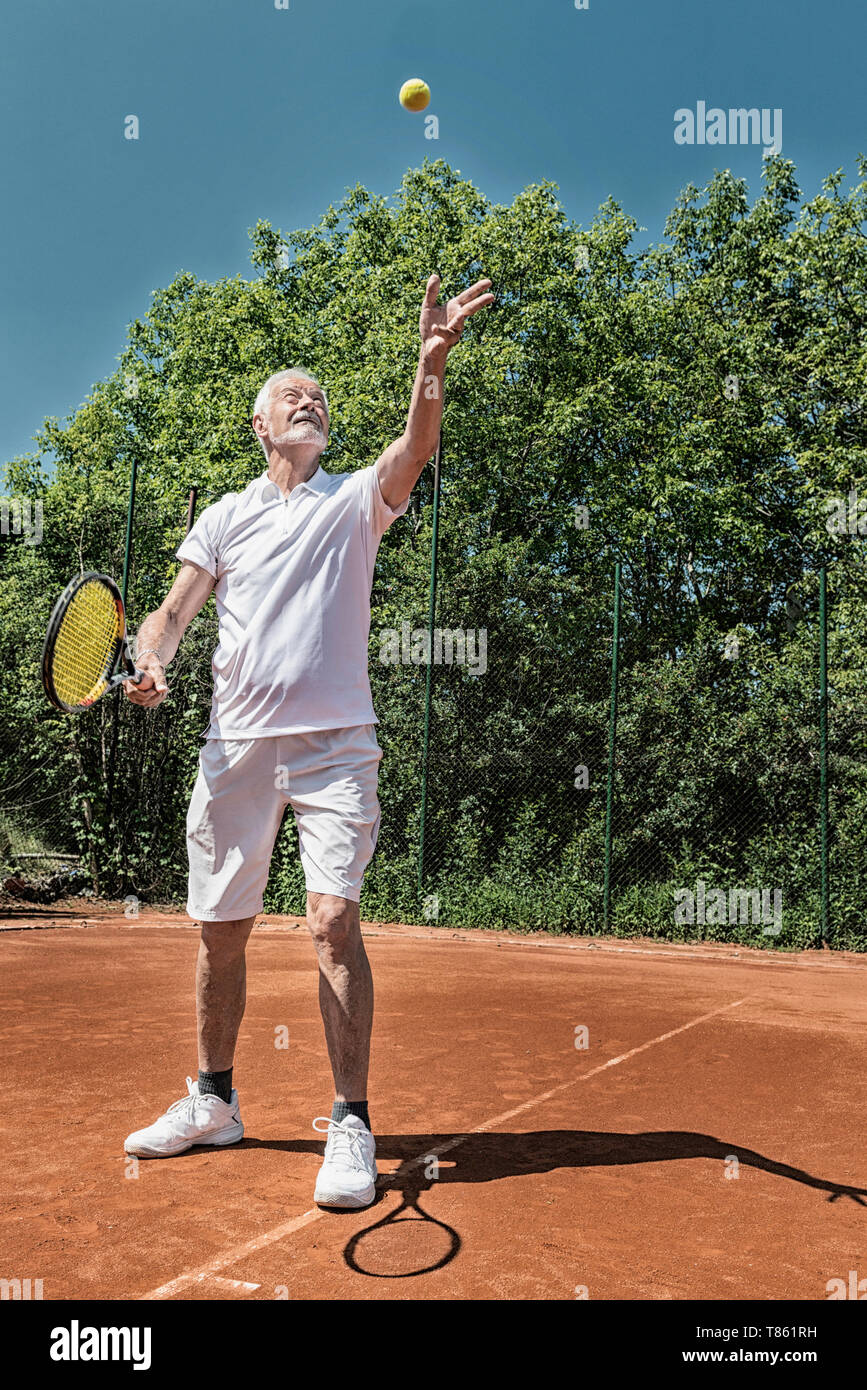 Senior tennis player serving Stock Photo - Alamy