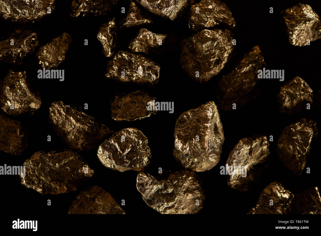 top view of scattered shiny golden stones isolated on black Stock Photo ...