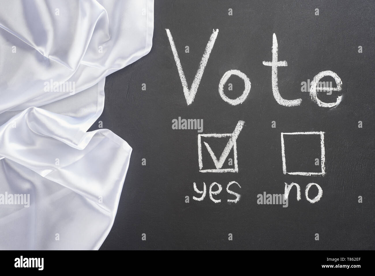 top view of white vote lettering and check mark near yes word on black ...