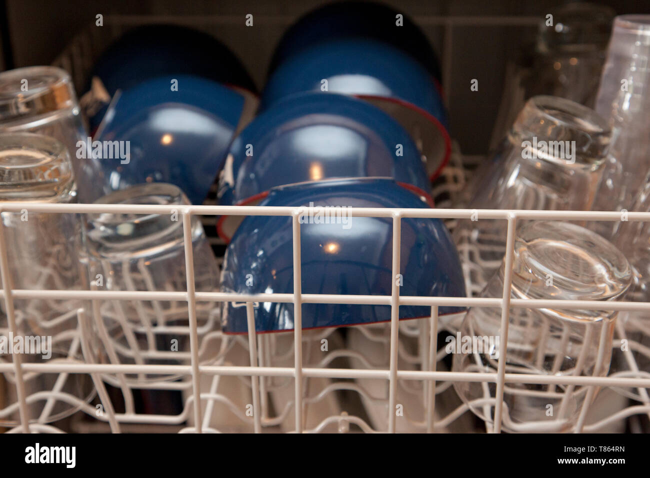 A top rack on a dishwasher with blue bowls and clear glasses Stock ...