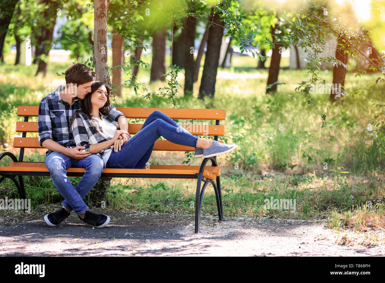 Young couple resting on bench in green park Stock Photo - Alamy