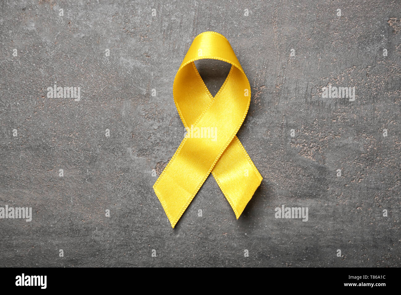 Yellow ribbon on grey background. Cancer concept Stock Photo - Alamy