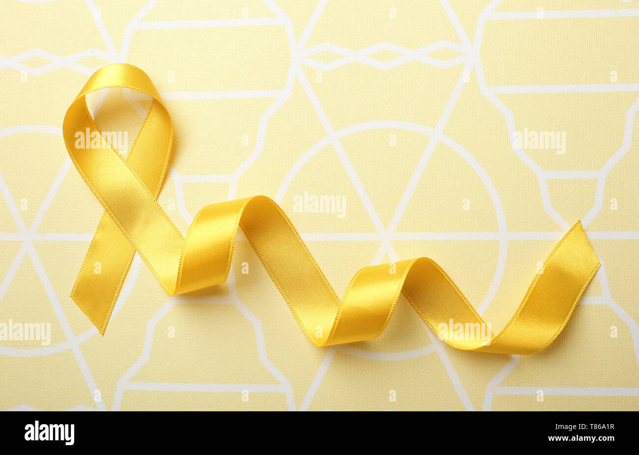 Yellow ribbon on color background. Cancer concept Stock Photo - Alamy