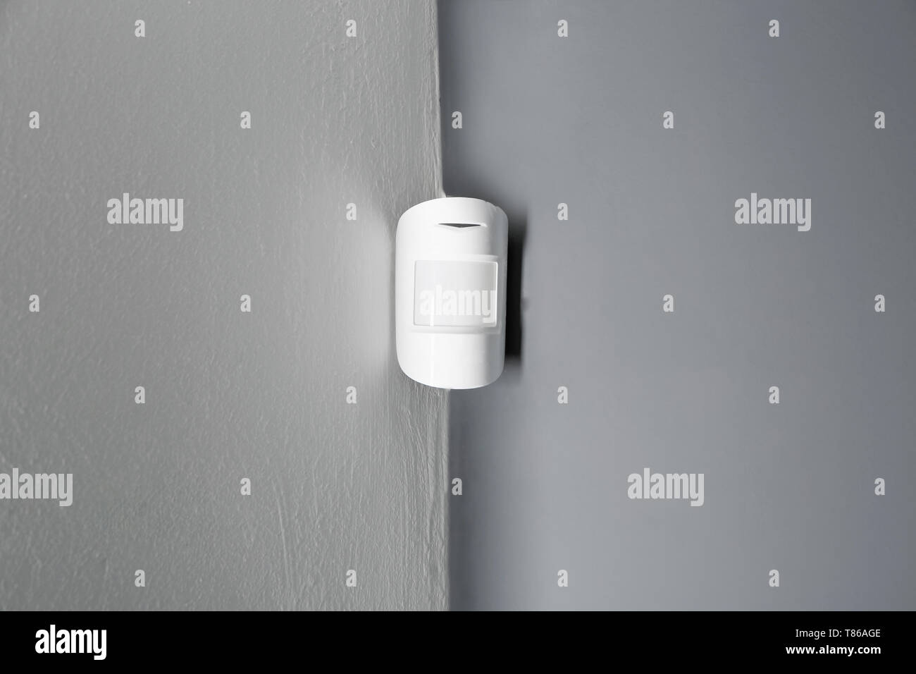 Modern motion sensor on wall indoors Stock Photo - Alamy