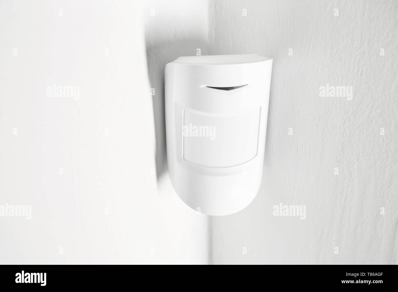 Modern motion sensor on wall indoors Stock Photo - Alamy
