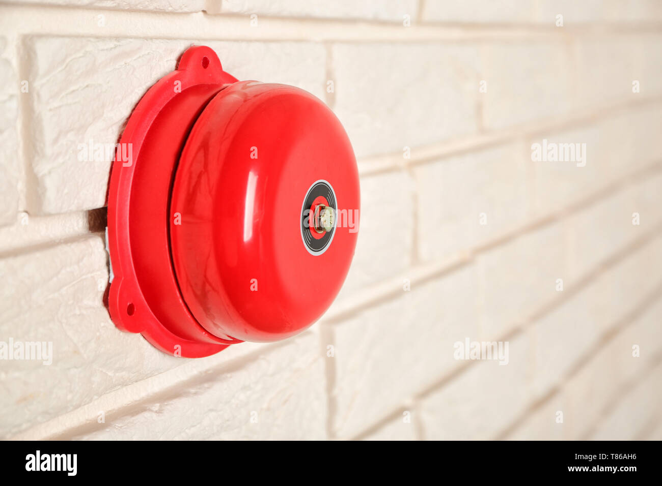 Modern alarm bell on brick wall indoors Stock Photo - Alamy