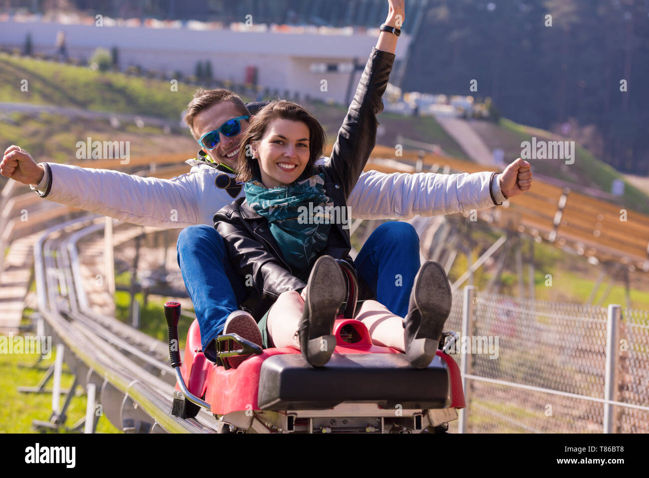 Excited young couple driving alpine coaster while enjoying beautiful ...