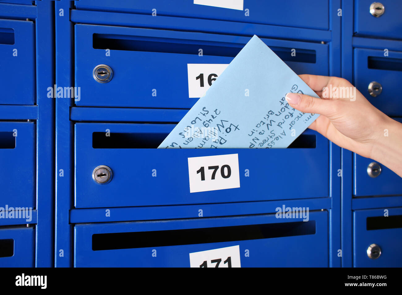 Woman putting letter into mailbox Stock Photo - Alamy