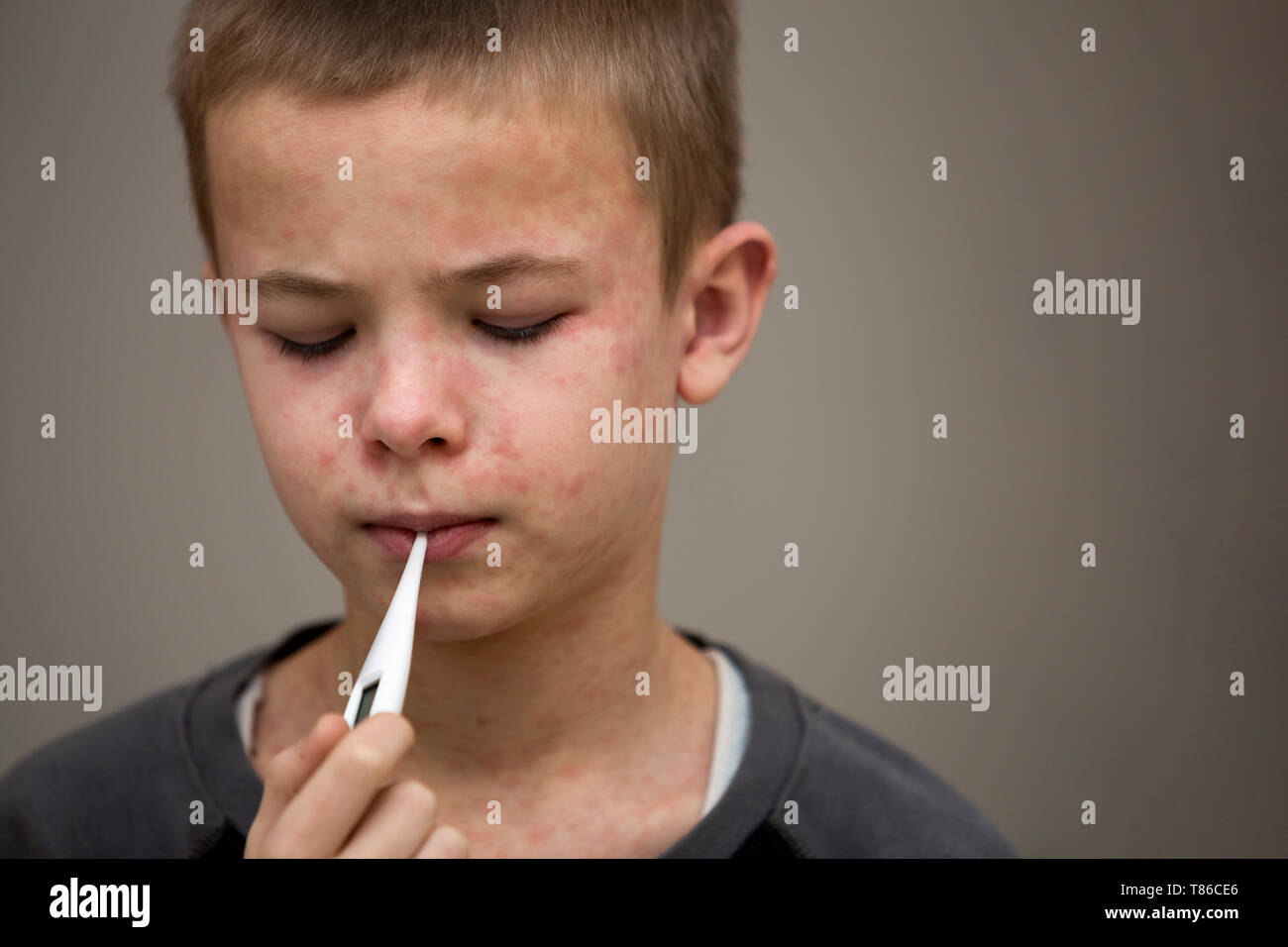 Portrait of sick sad boy child with thermometer having fever suffering ...