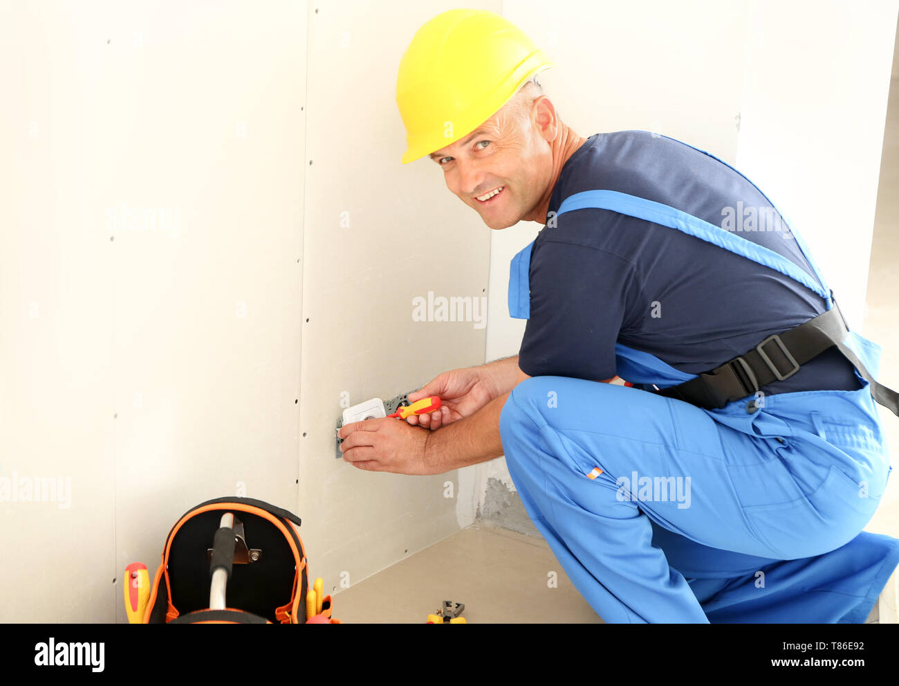 Male electrician repairing socket in flat Stock Photo - Alamy