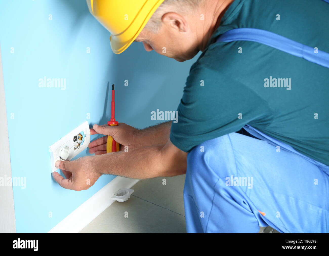 Male electrician repairing socket in flat Stock Photo - Alamy