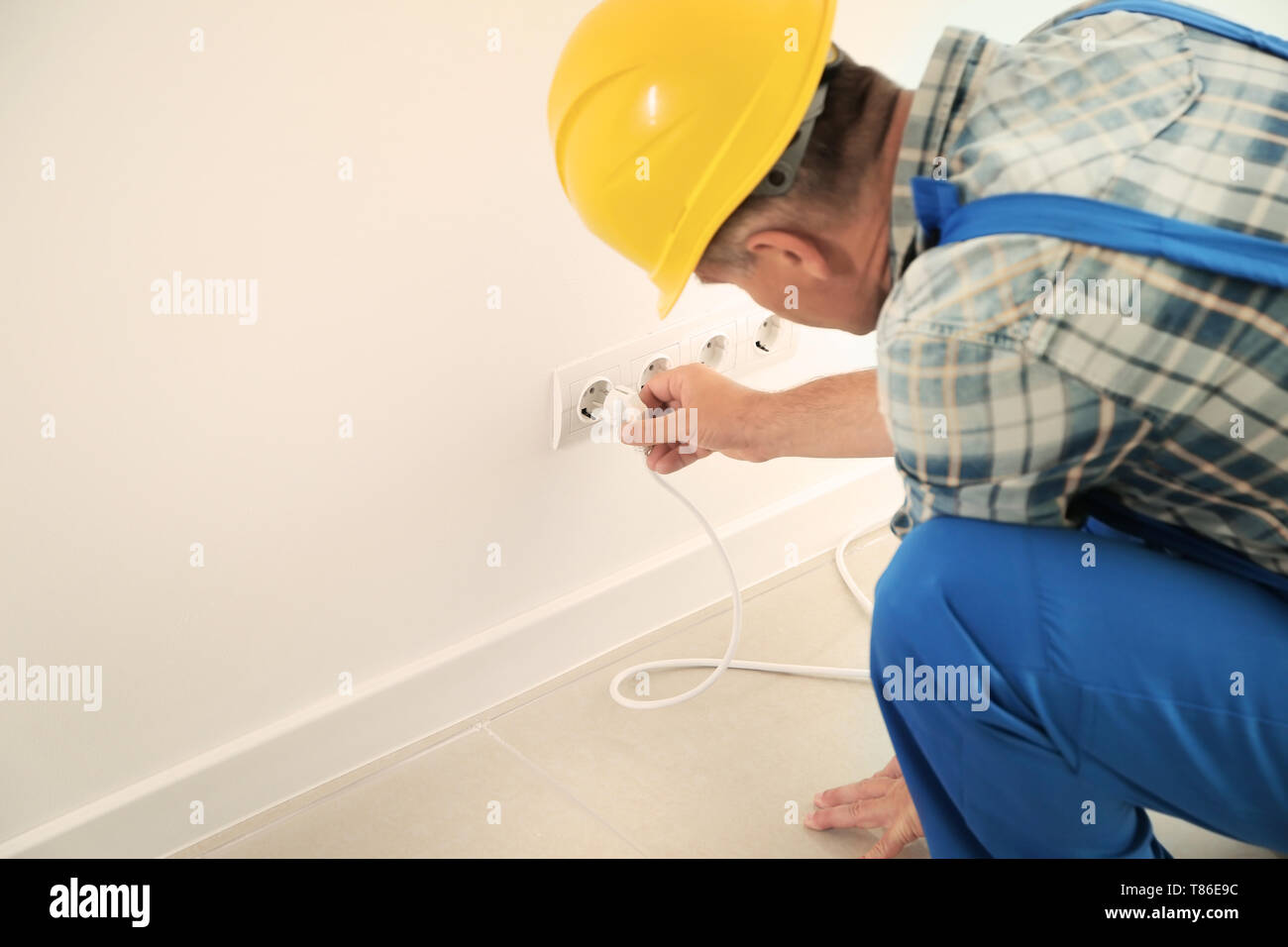 Male electrician inserting plug into socket in order to check its ...