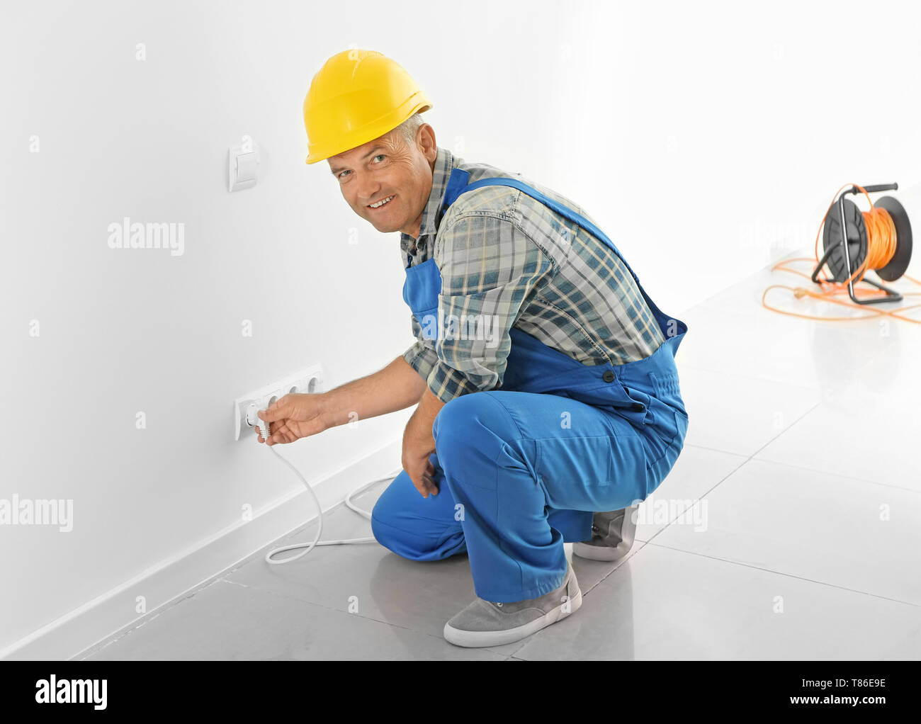 Male electrician inserting plug into socket in order to check its ...