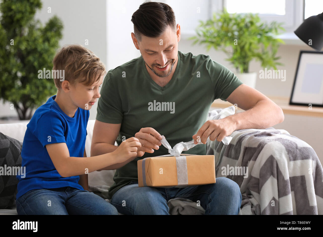 Man opening gift for Father's Day from his son at home Stock Photo - Alamy